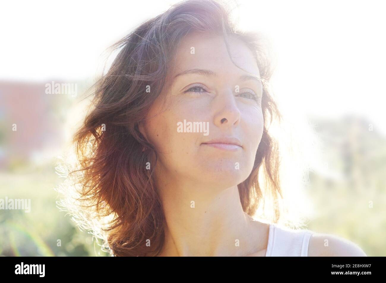 Crop happy adult lady with wavy hair looking away dreamily while ...