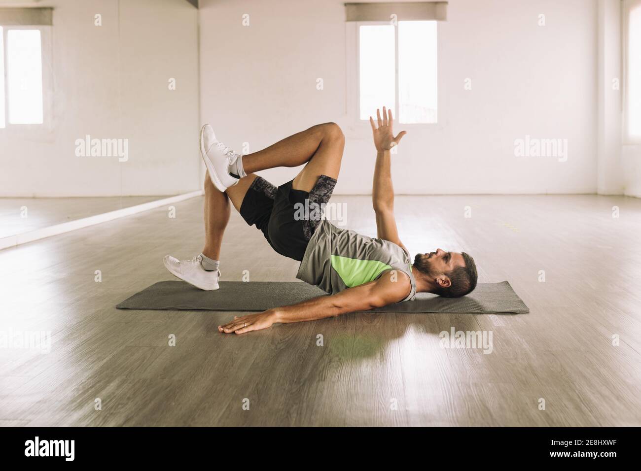 Side view of muscular young bearded male athlete lying on mat near ...