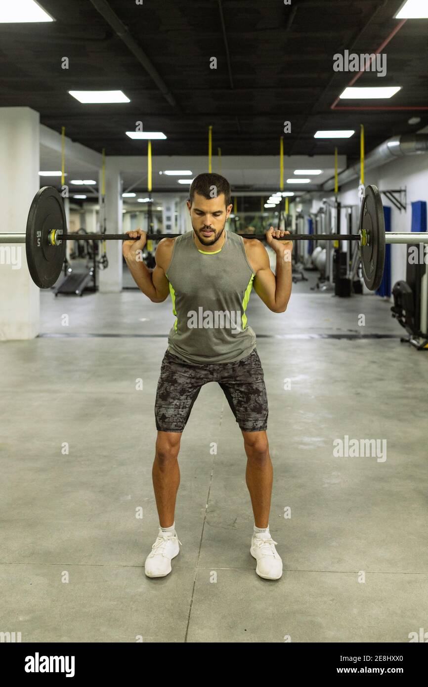 Full body of strong young muscular male athlete in activewear lifting ...
