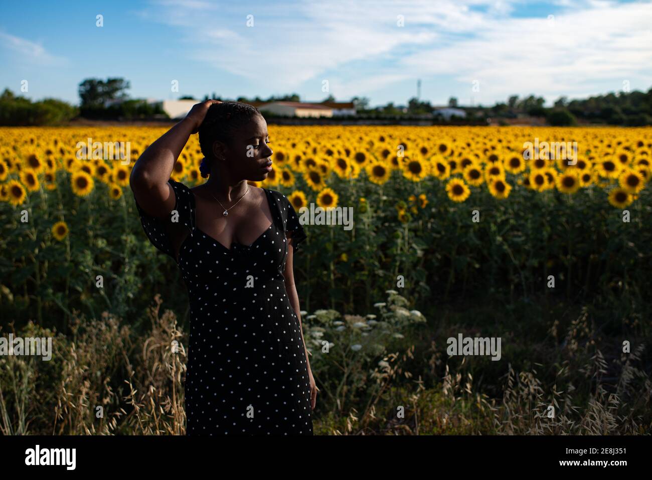 African American female in dress standing on background of blossoming ...