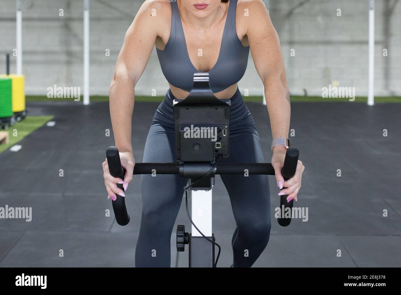 Determined muscular female athlete in sportswear riding stationary ...