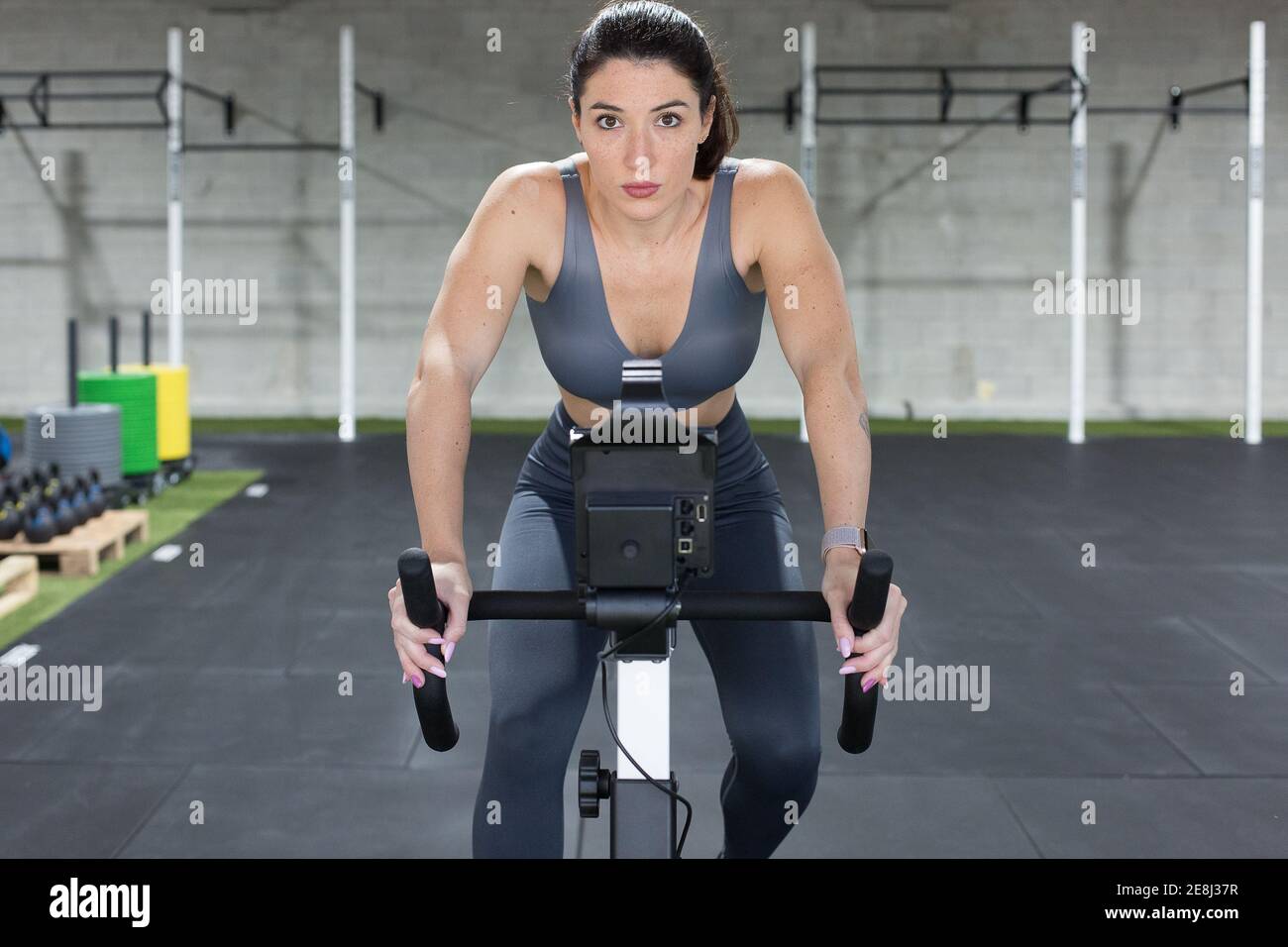 Determined muscular female athlete in sportswear riding stationary ...