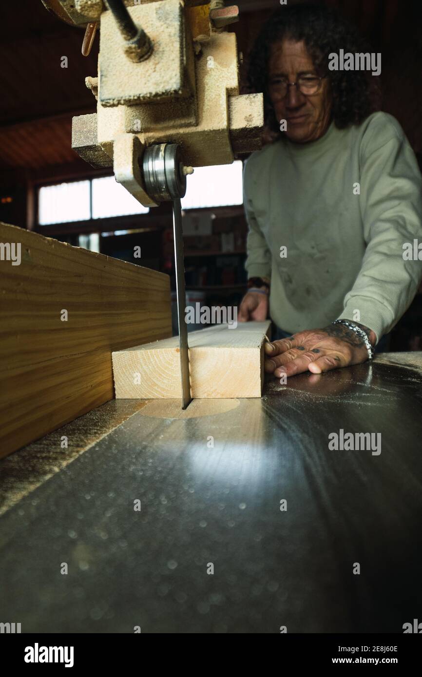 From below middle aged male carpenter without a thumb cutting piece of ...