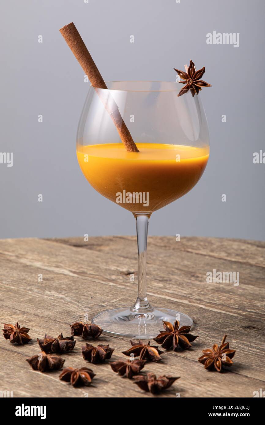 Orange fruity cocktail with cinnamon stick and star anise in a glass ...
