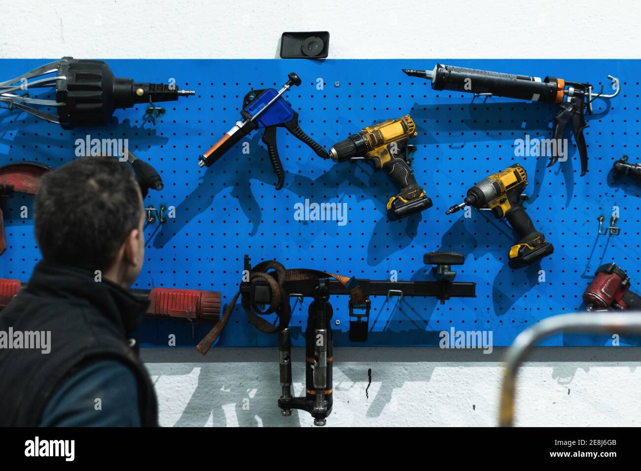 Side view of unrecognizable male master in vest standing in garage and ...