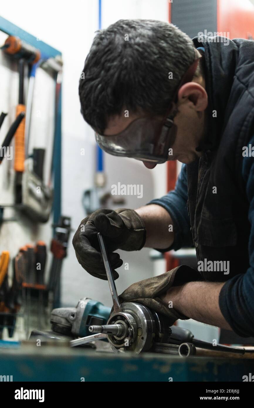 Side view of concentrated adult male auto mechanic in protective ...