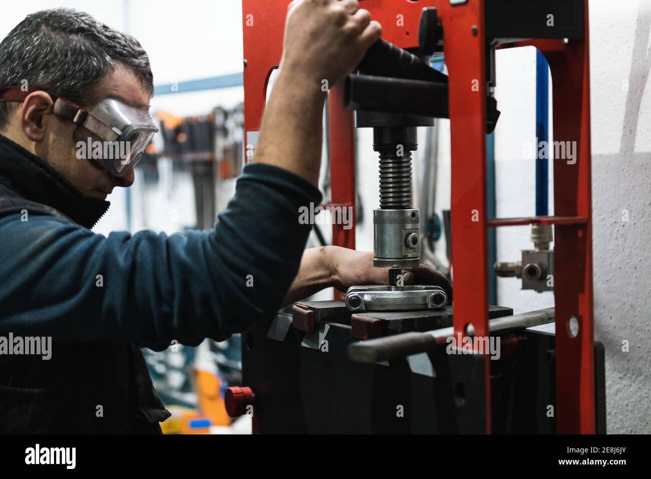 Side view of attentive adult male auto mechanic in protective goggles ...