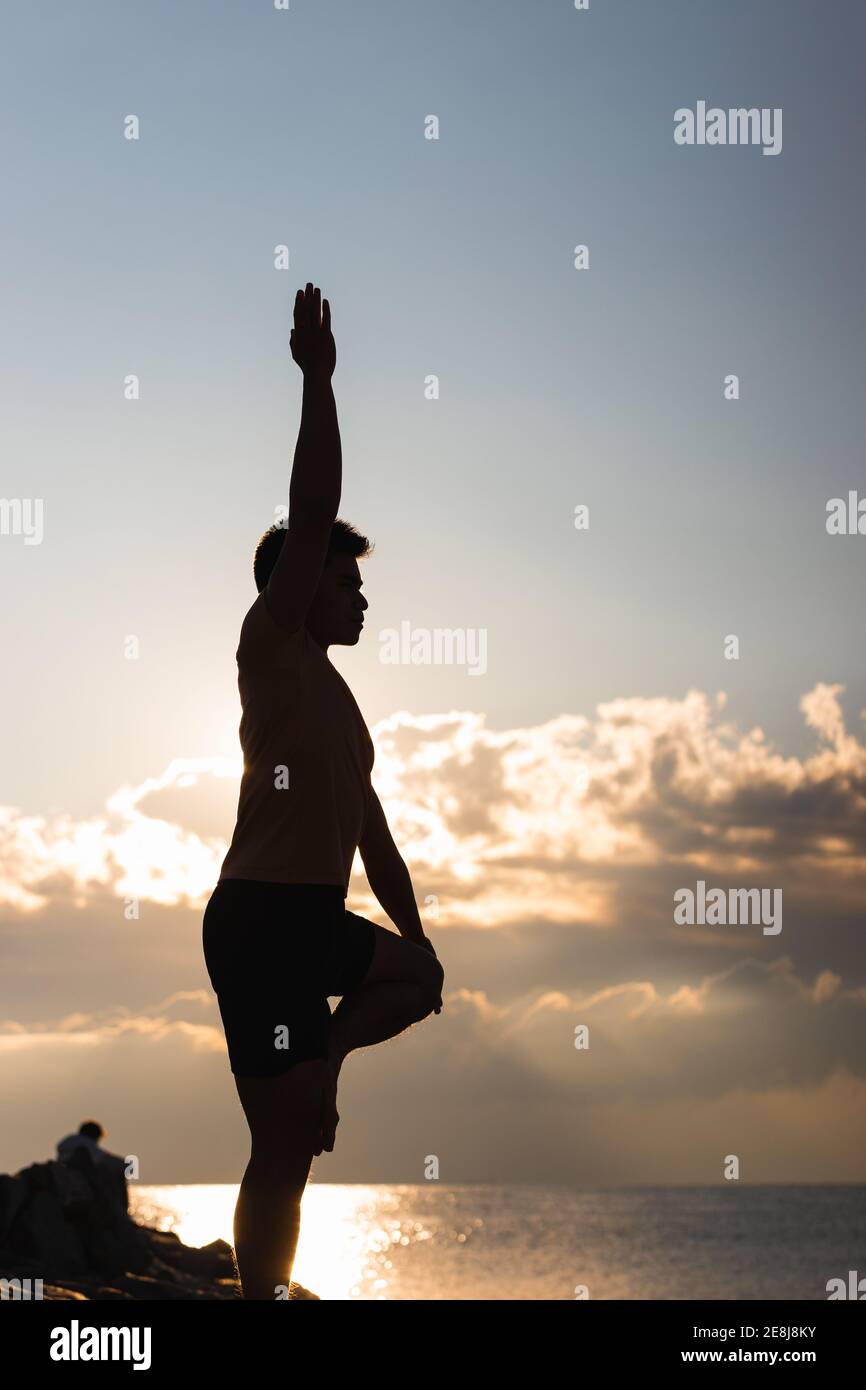 Side view silhouette of unrecognizable male balancing on Tree pose with ...