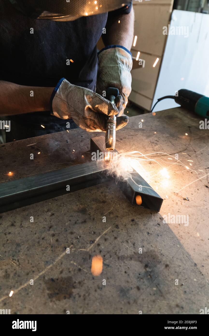 From above of crop unrecognizable welder in protective gloves welding ...