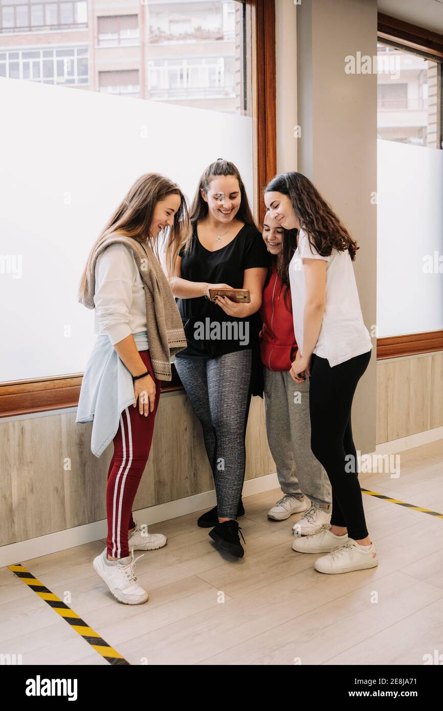 High angle of young smiling female dancers gathering in hall and ...