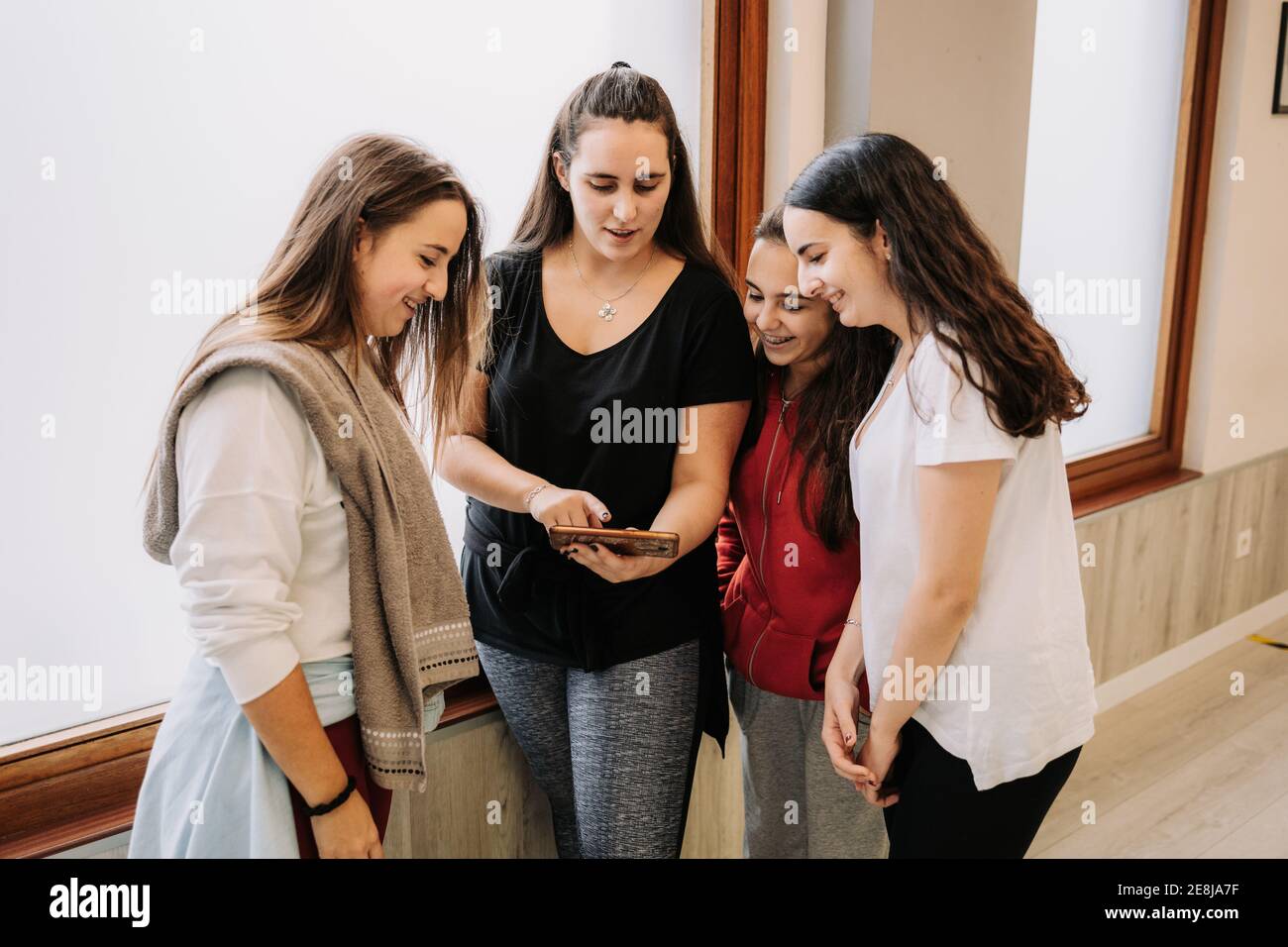High angle of young smiling female dancers gathering in hall and ...
