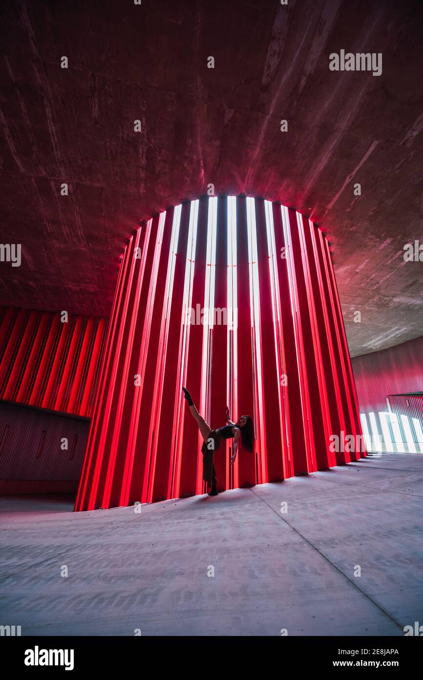 Side view of anonymous female theater artist stretching leg while ...