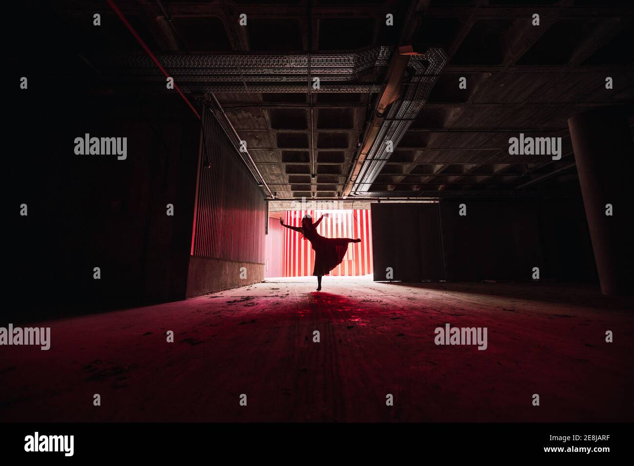 Anonymous female dancer in dress dancing with raised arms and leg on ...