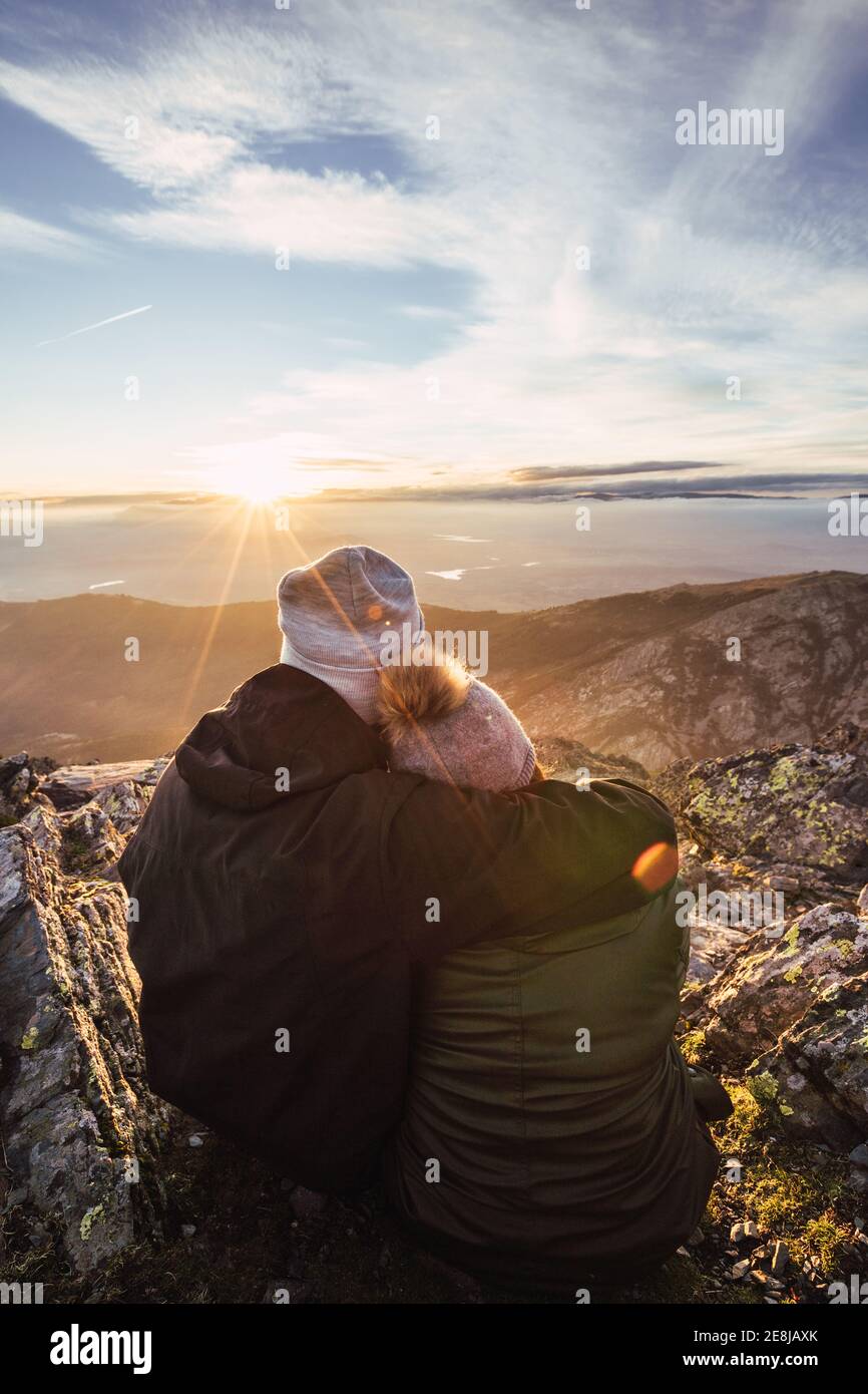 Back view of unrecognizable man embracing girlfriend in outerwear while ...