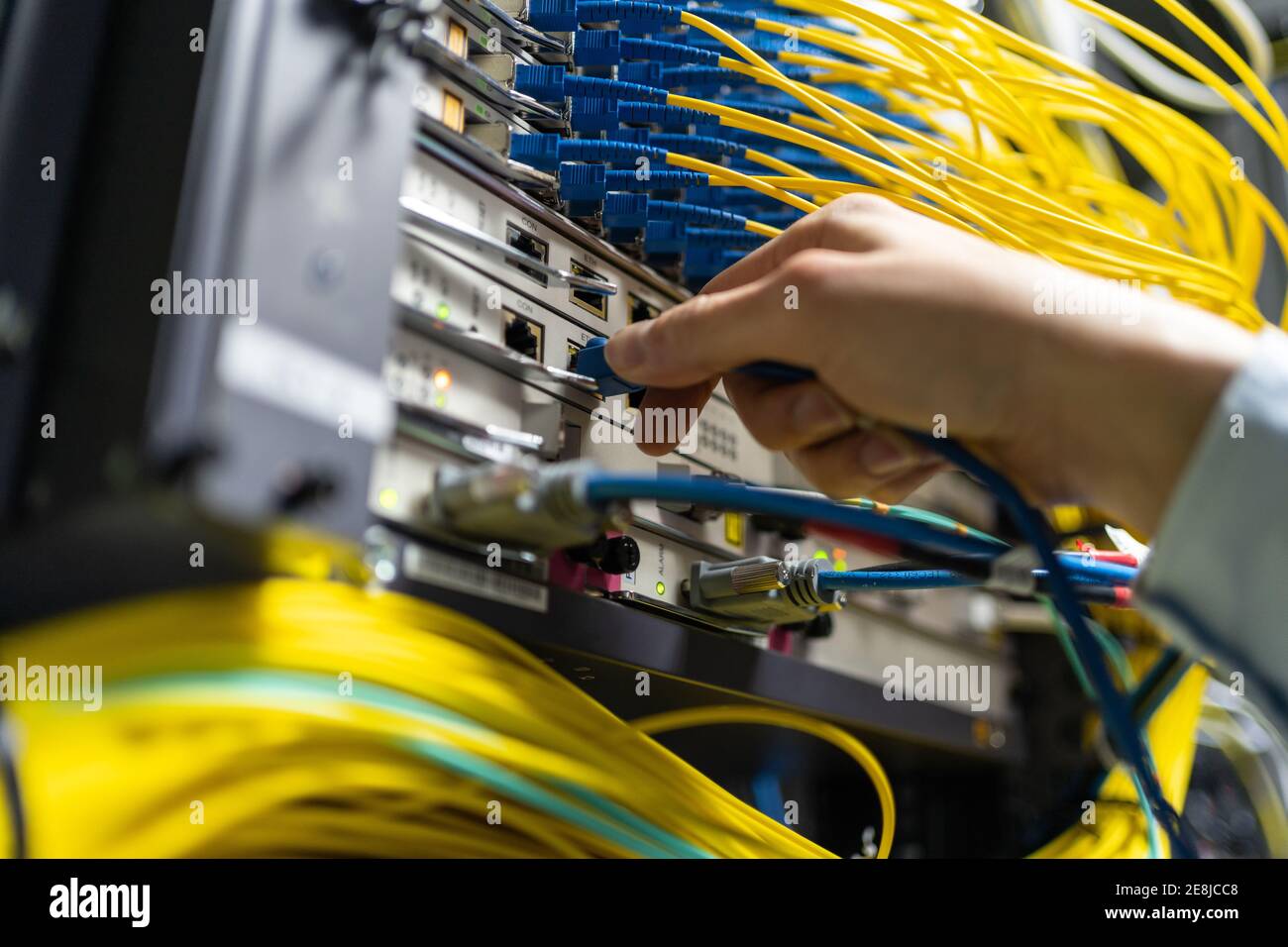 From below of crop anonymous man putting electronic cable in data ...