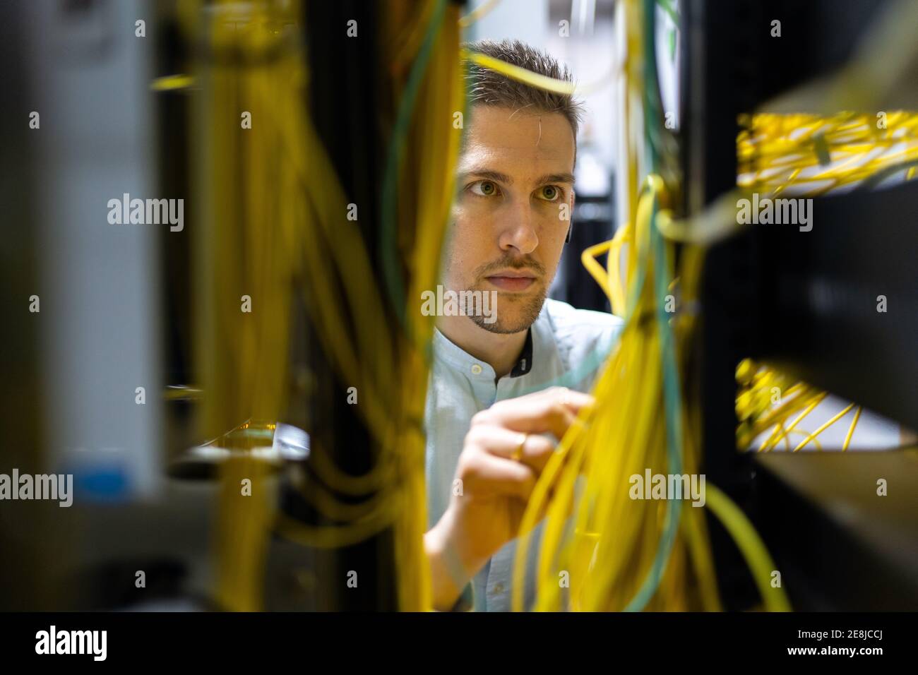 Concentrated male specialists working with wires in server while ...
