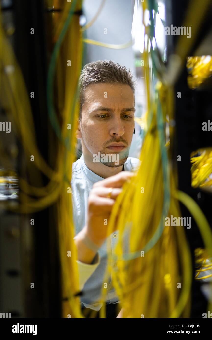 Concentrated male specialists working with wires in server while ...