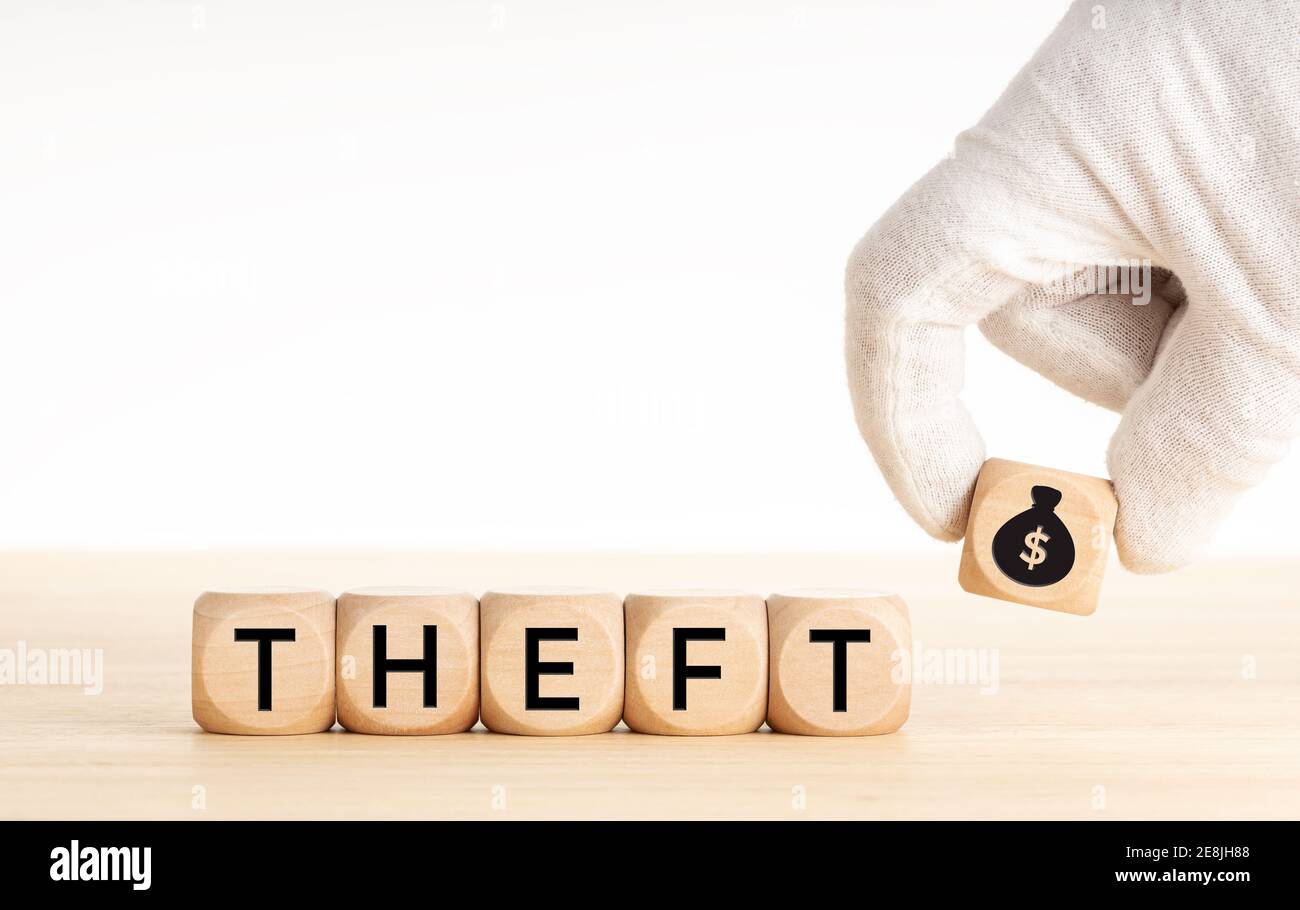 Theft concept. Hand picking a wooden block whit money bag icon and text ...