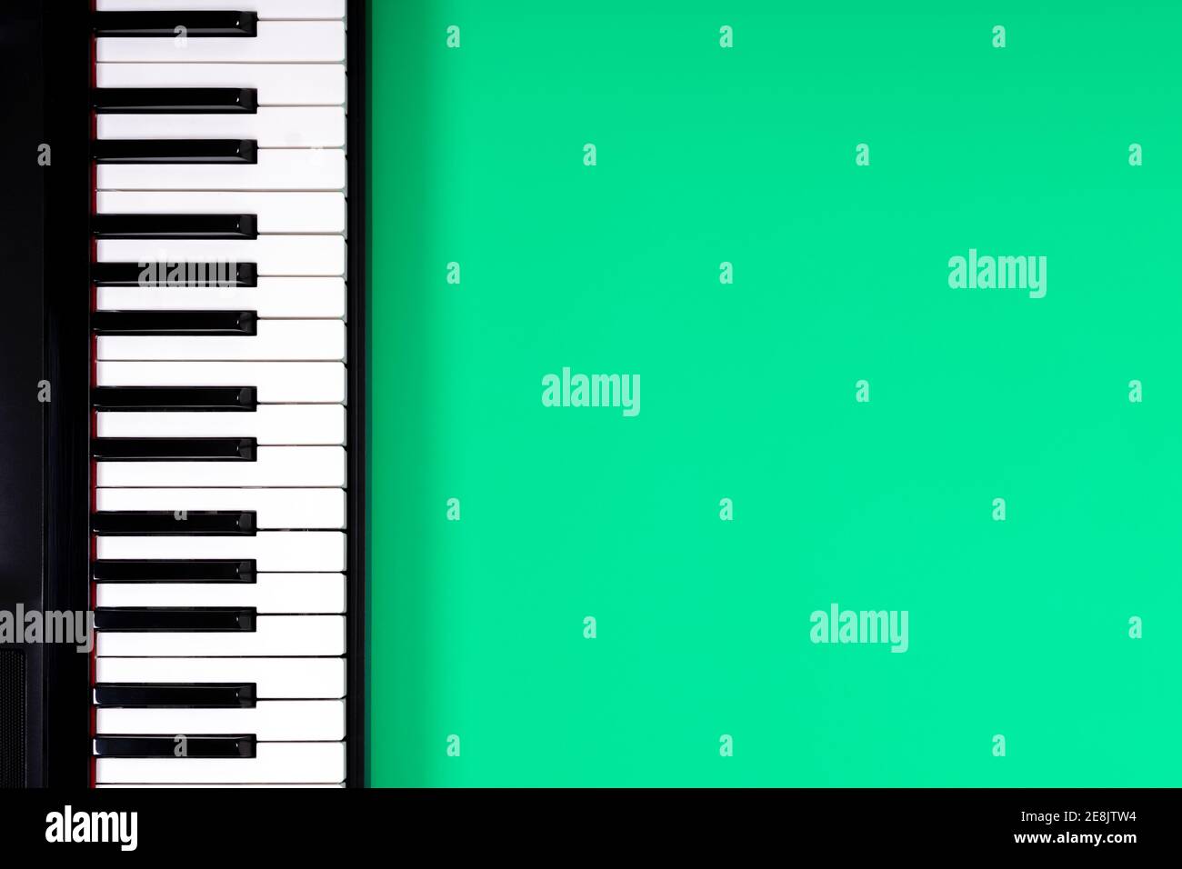 Black piano keyboard on light green background. Music learning concept ...