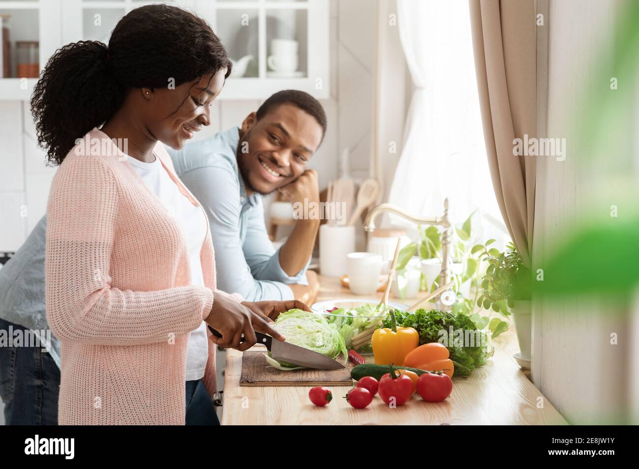 Smiling black couple cooking in kitchen together, preparing healthy ...