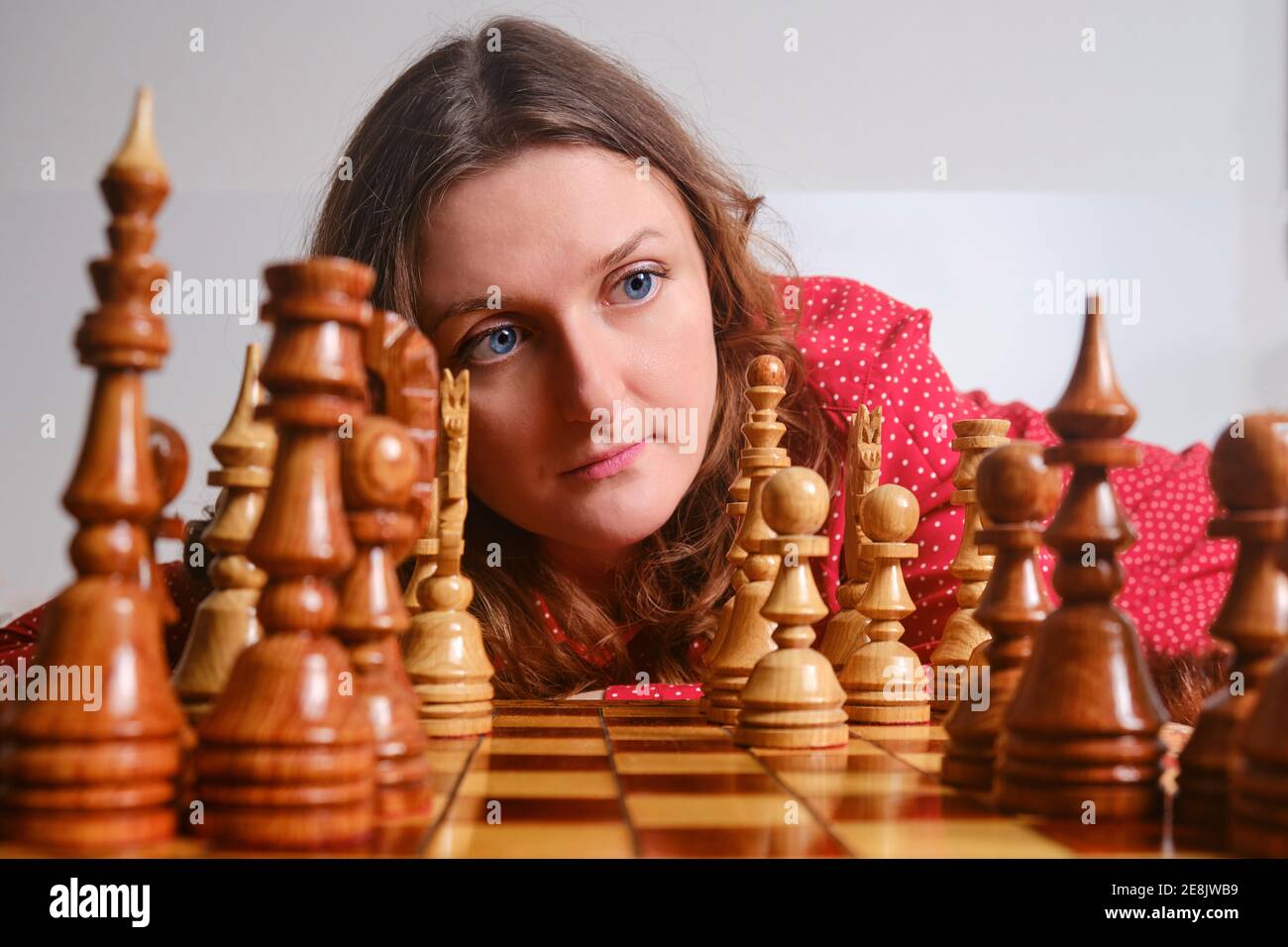 Adult woman playing chess while sitting on the bed at the chessboard ...