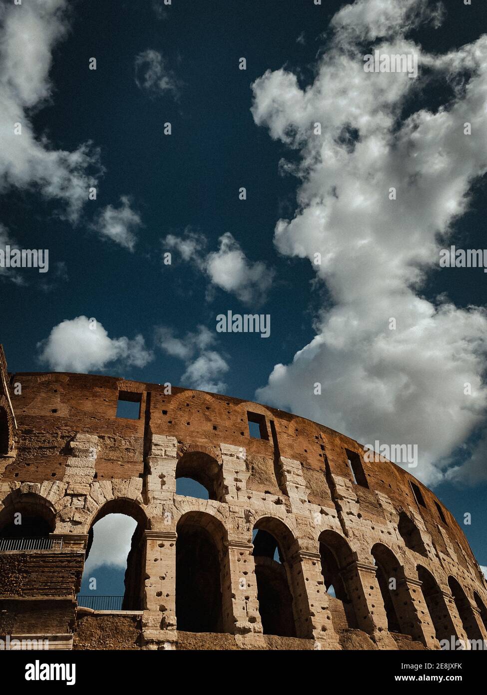 A vertical shot of Colosseum under blue sky and white clouds Stock ...