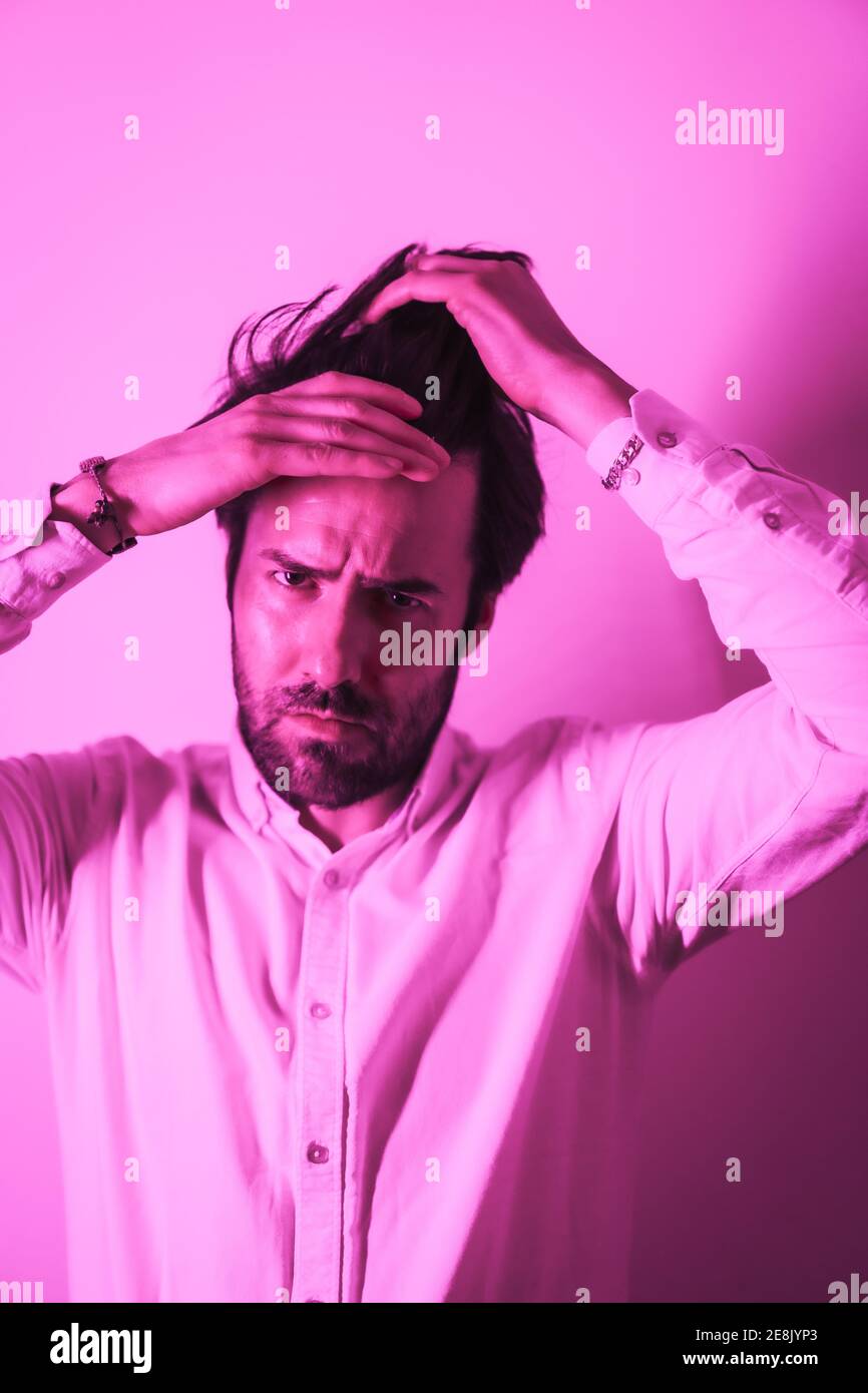 A vertical portrait of a handsome caucasian bearded young male touching ...