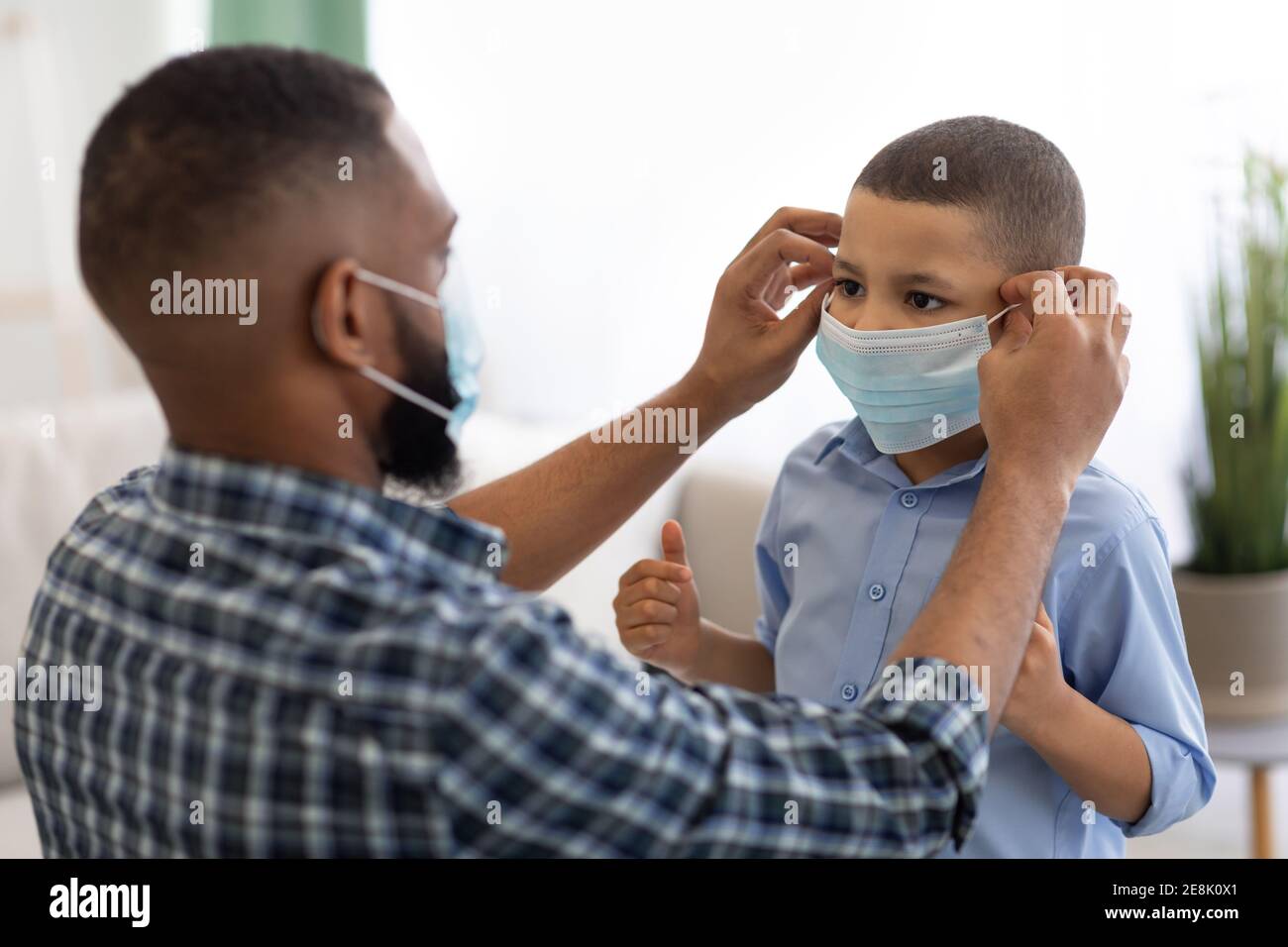 Black Dad Putting Protective Surgical Mask On Son's Face Indoors Stock ...