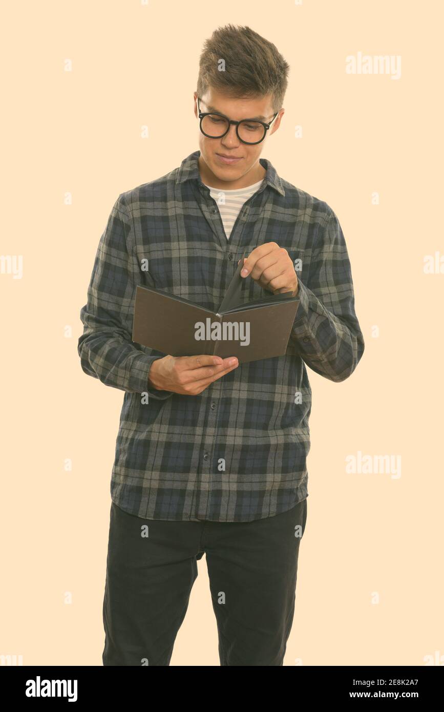 Studio shot of young handsome man standing while reading book Stock ...