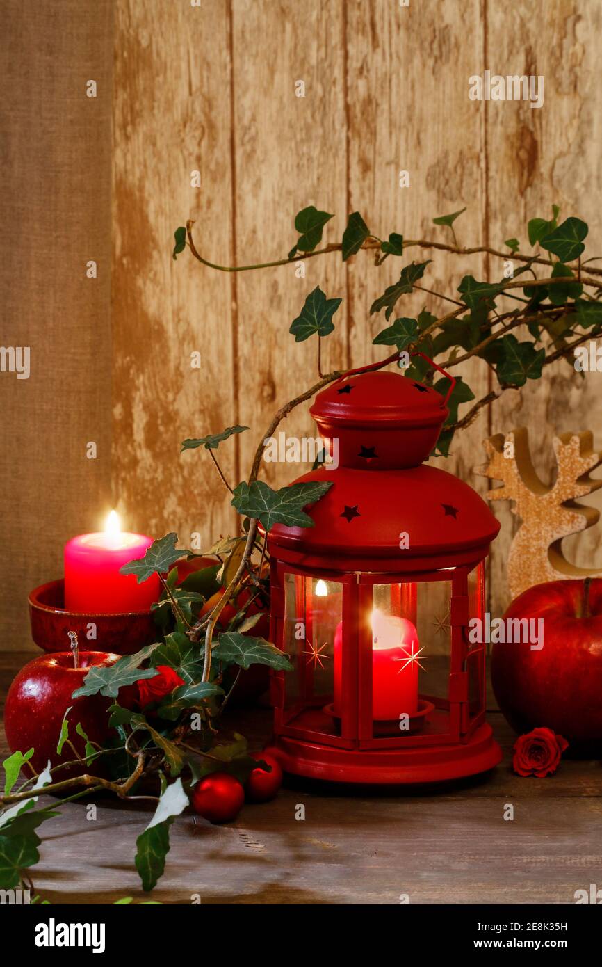 Christmas decoration with red lantern, candle, apples and ivy leaves ...