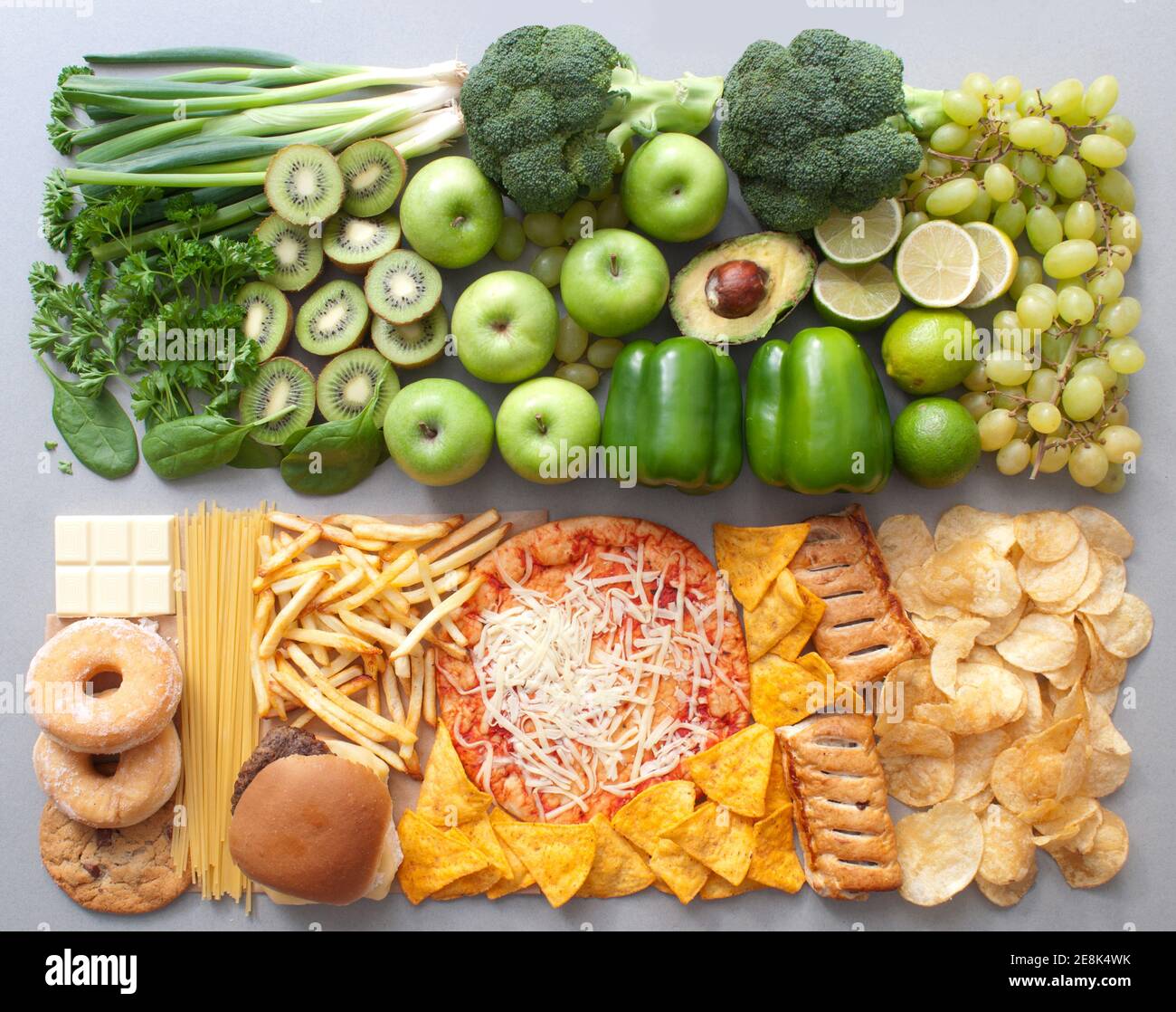 Assorted group of green fruits and vegetables alongside beige junk food ...