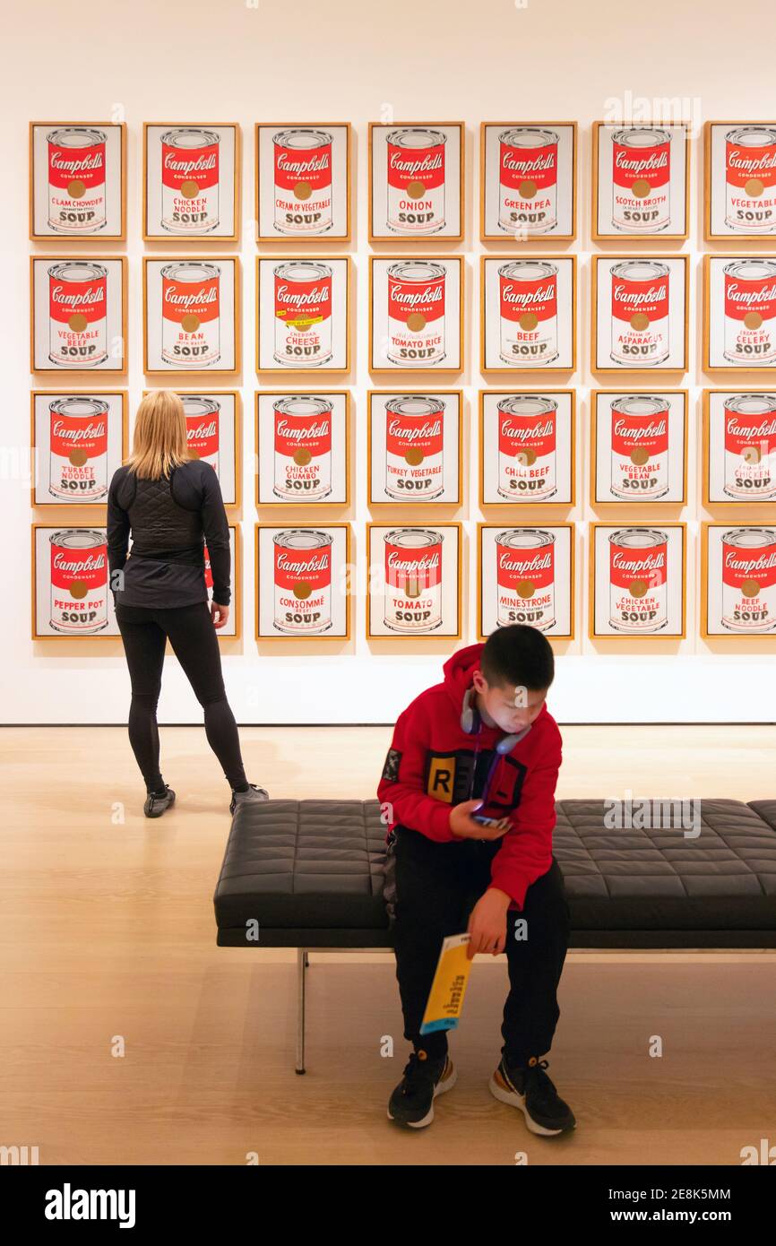 woman looking at multiple prints of Andy Warhol's Campbells soup can ...