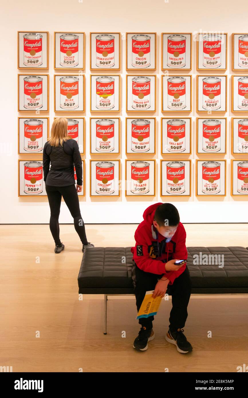 woman looking at multiple prints of Andy Warhol's Campbells soup can ...