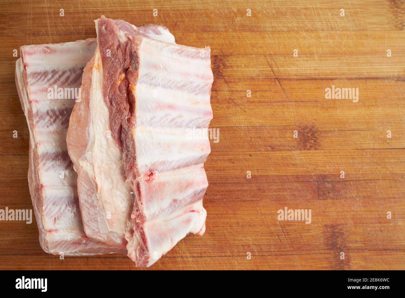 fresh raw pork ribs on a wooden board background. two pieces ...