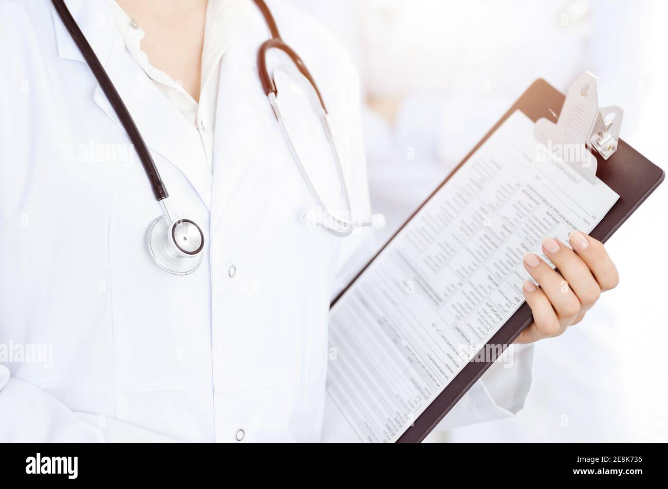 Unknown woman-doctor standing straight with clipboard of medication ...