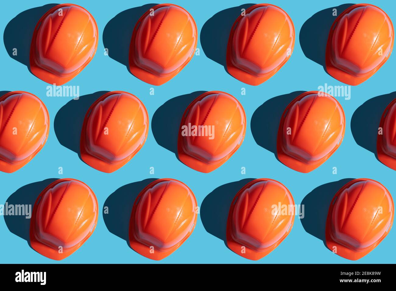 orange safety helmet rows on a blue background with hard shadows ...