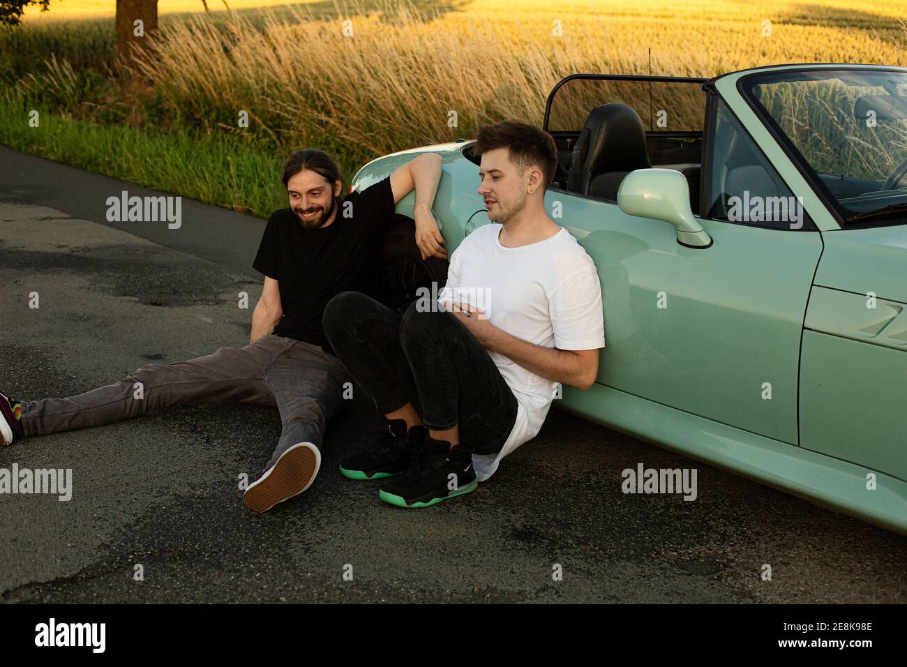 White young european models boys outside sitting on the road near car ...