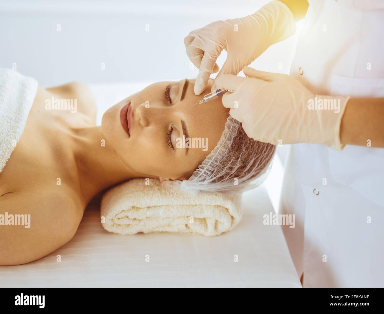 Beautiful woman receiving beauty injections with closed eyes in sunny ...