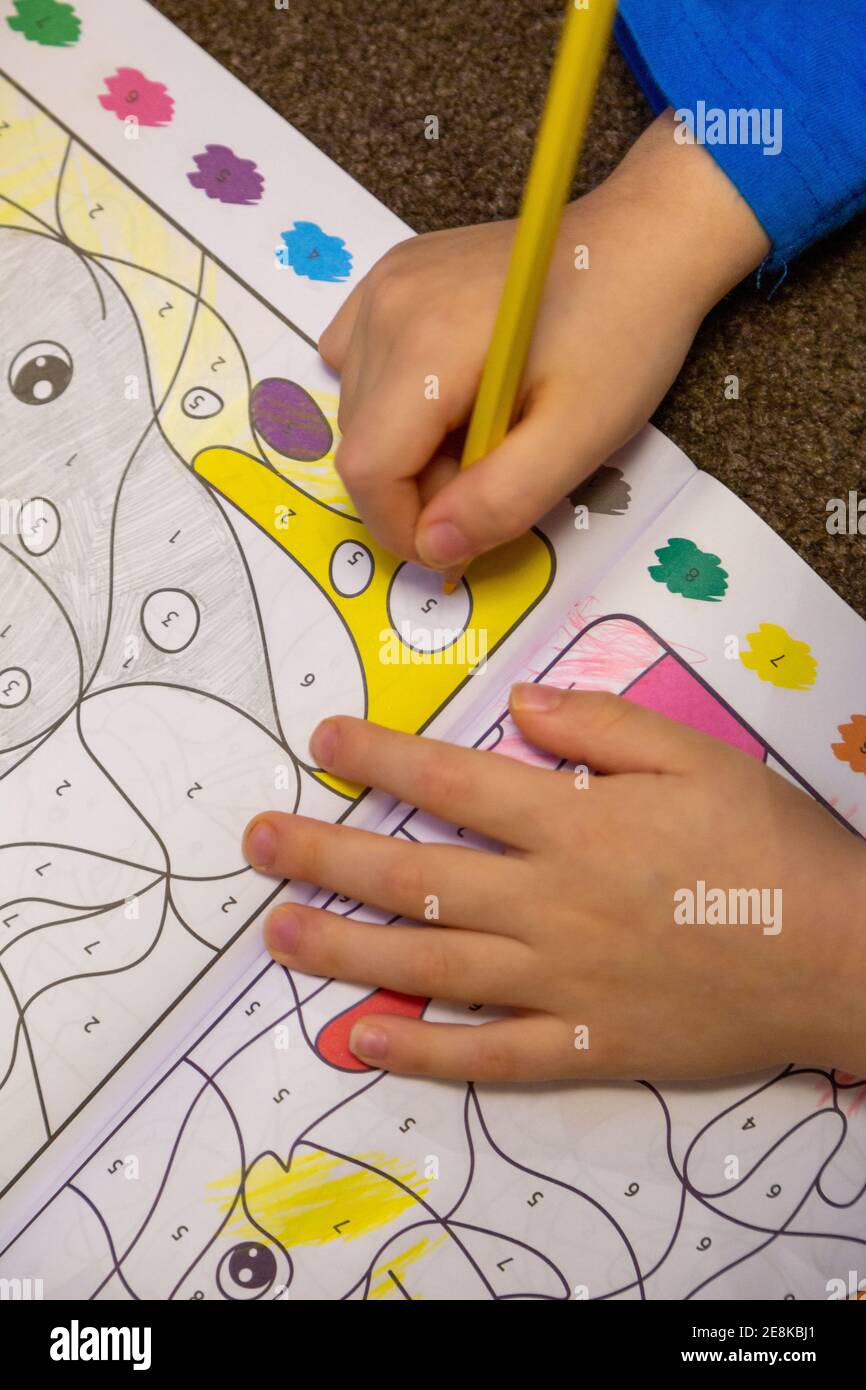 a childs hands using a colouring pen to colour a colouring in book ...