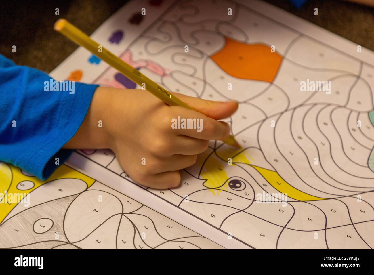a childs hands using a colouring pen to colour a colouring in book ...