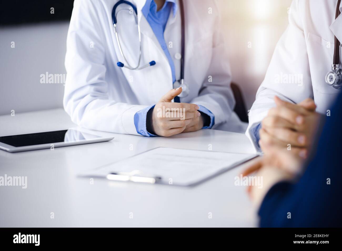 Two doctors and patient woman discussing something while sitting at the ...