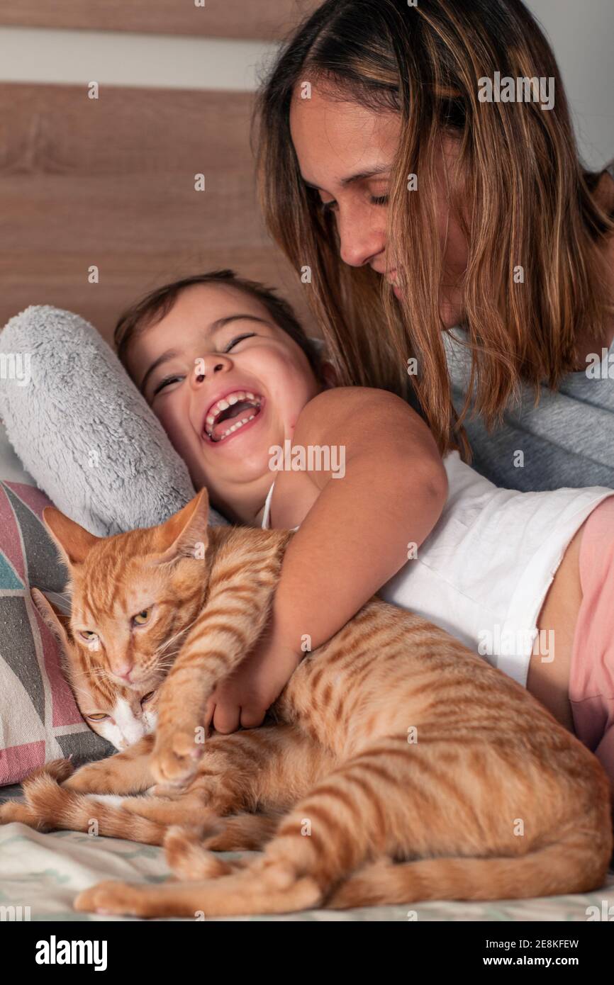 Caucasian mother and daughter, playing with their little tabby cat on ...