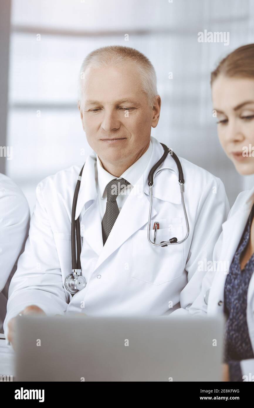 Doctors colleagues and elderly therapist discussing current disease ...