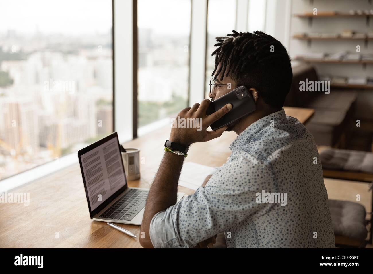 Black man reading text on pc calling lawyer by cell Stock Photo - Alamy