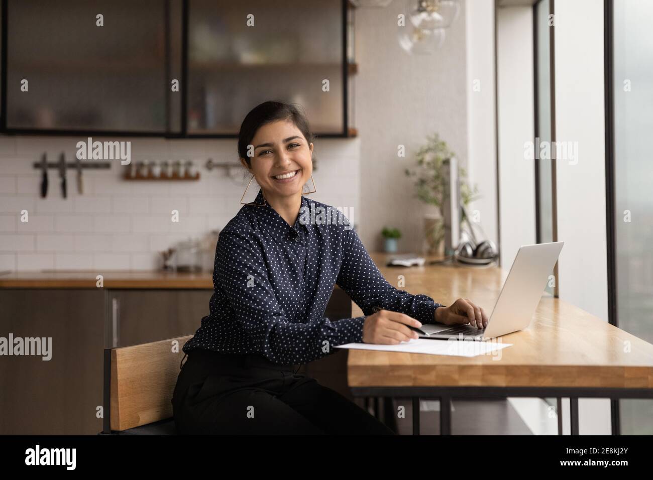 Smiling indian woman student using pc writing on paper sheet Stock ...