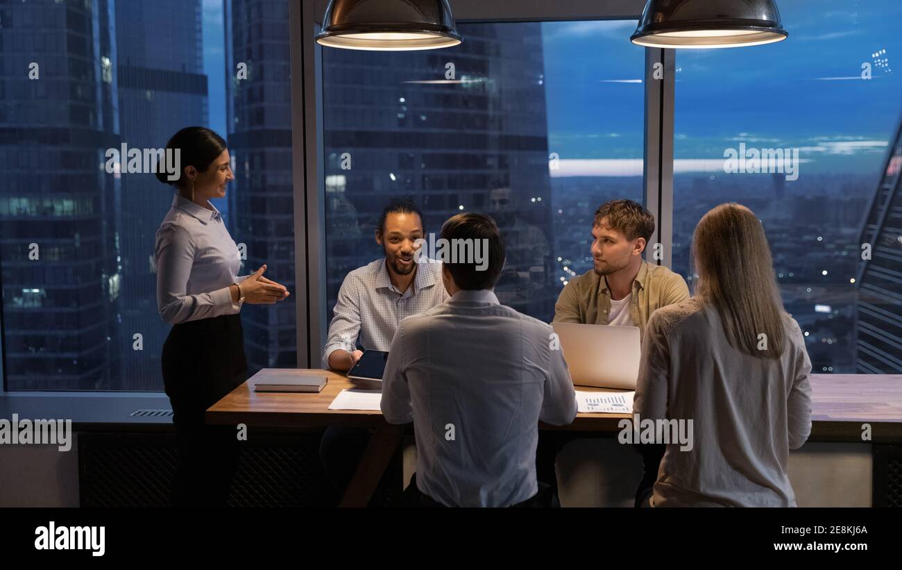 Multiracial business team sit around conference table by window wall ...