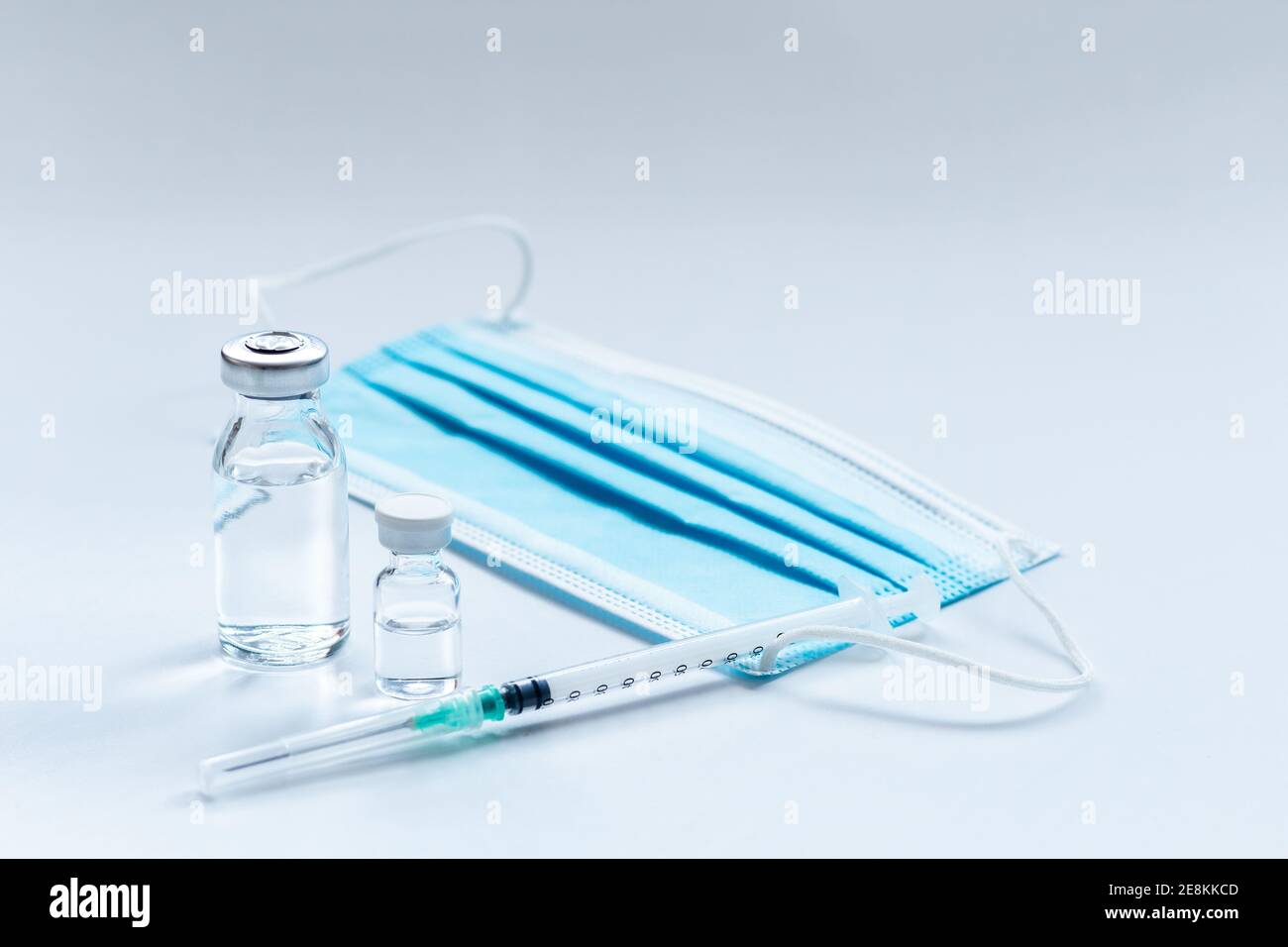 Vaccine vial, syringe and mask on white background Stock Photo - Alamy