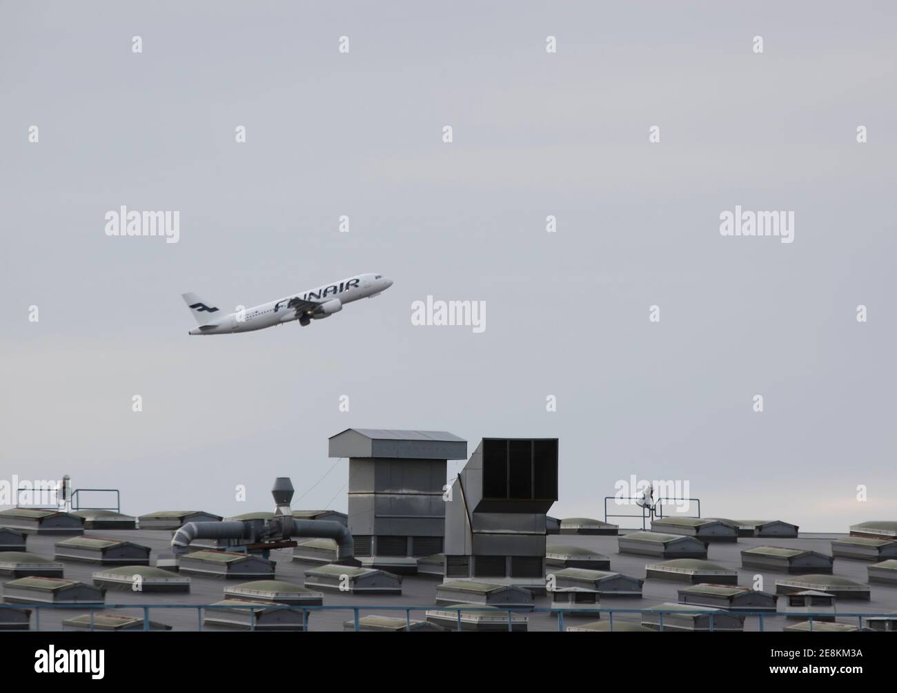 Airplane taking off over rooftop Stock Photo - Alamy