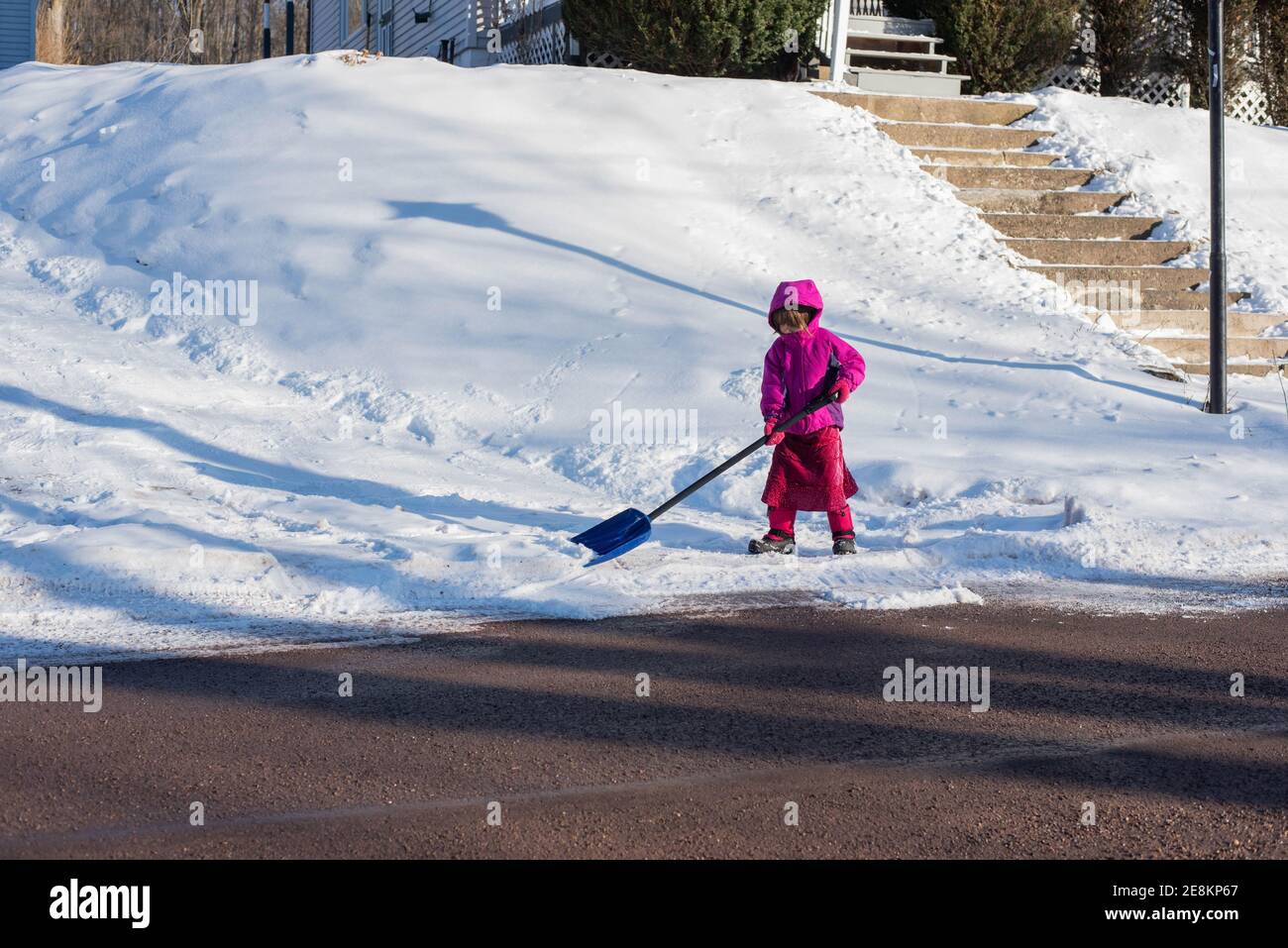 A young child shovels snow in rural Pennsylvania, USA in the winter of ...