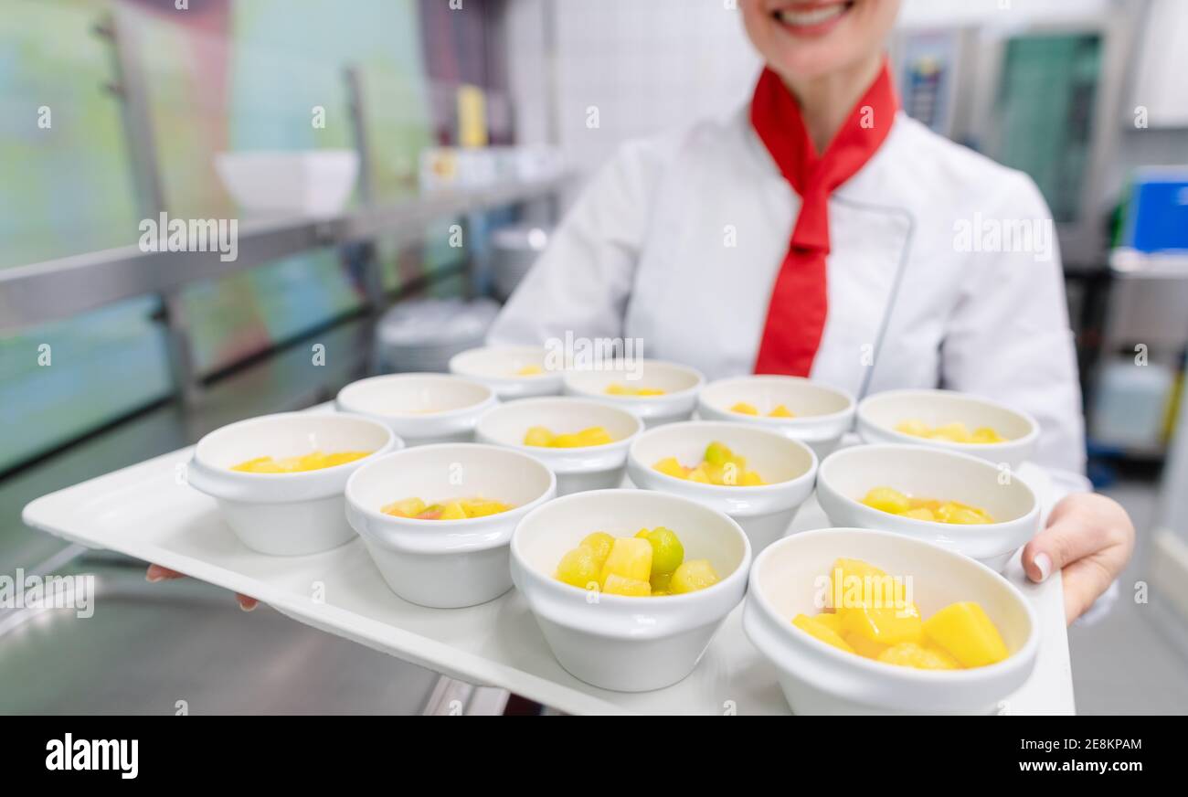 Cook in commercial kitchen showing tray with dessert Stock Photo - Alamy